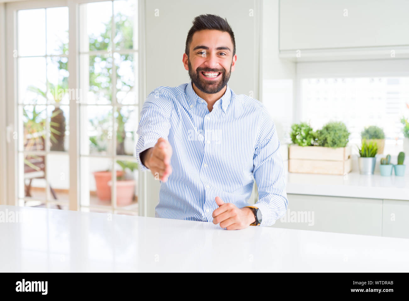Handsome hispanic business man smiling friendly offering handshake as ...