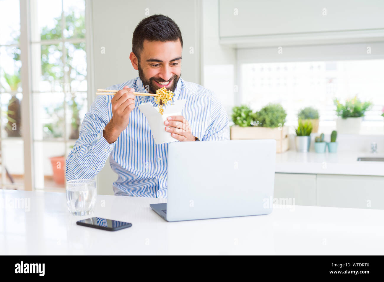 Business man eating asian food from delivery while working using ...