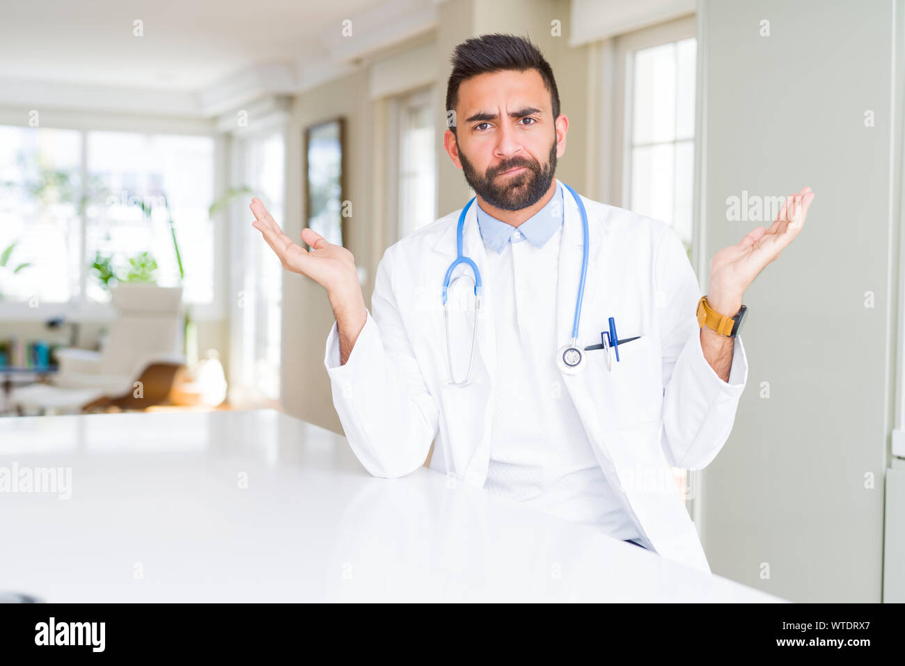 Handsome hispanic doctor man wearing stethoscope at the clinic clueless ...