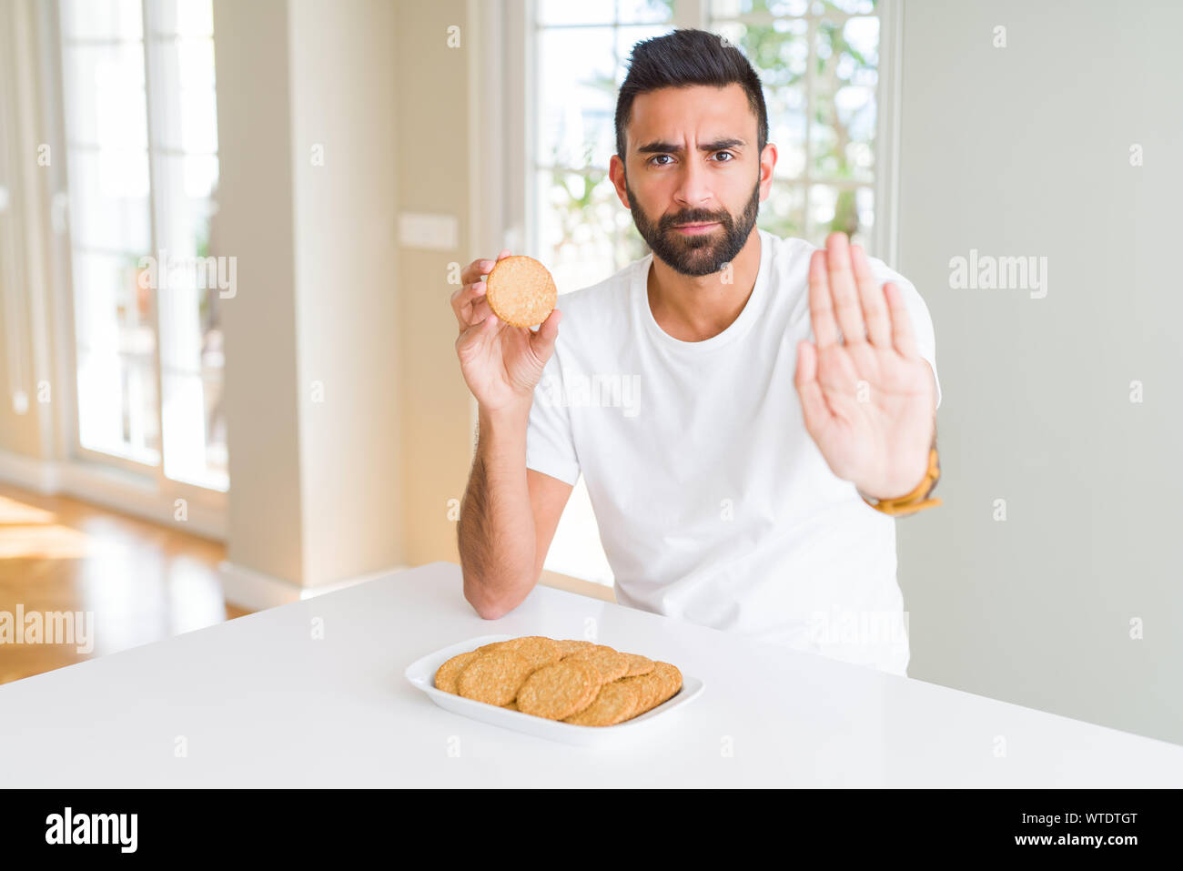 Handsome hispanic man eating healthy whole grain biscuits with open ...