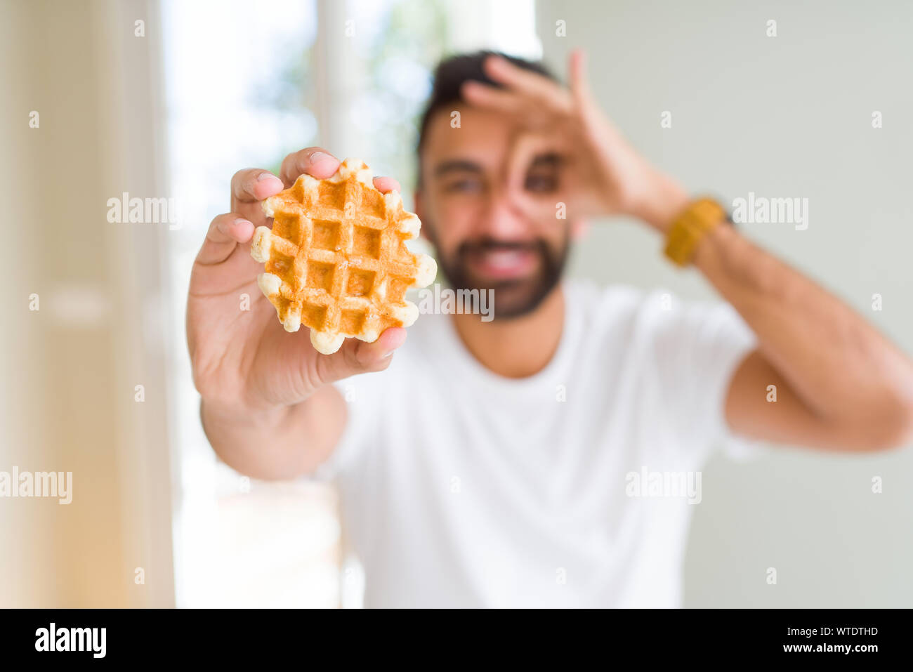 Handsome hispanic man eating sweet belgian waffle pastry with happy ...