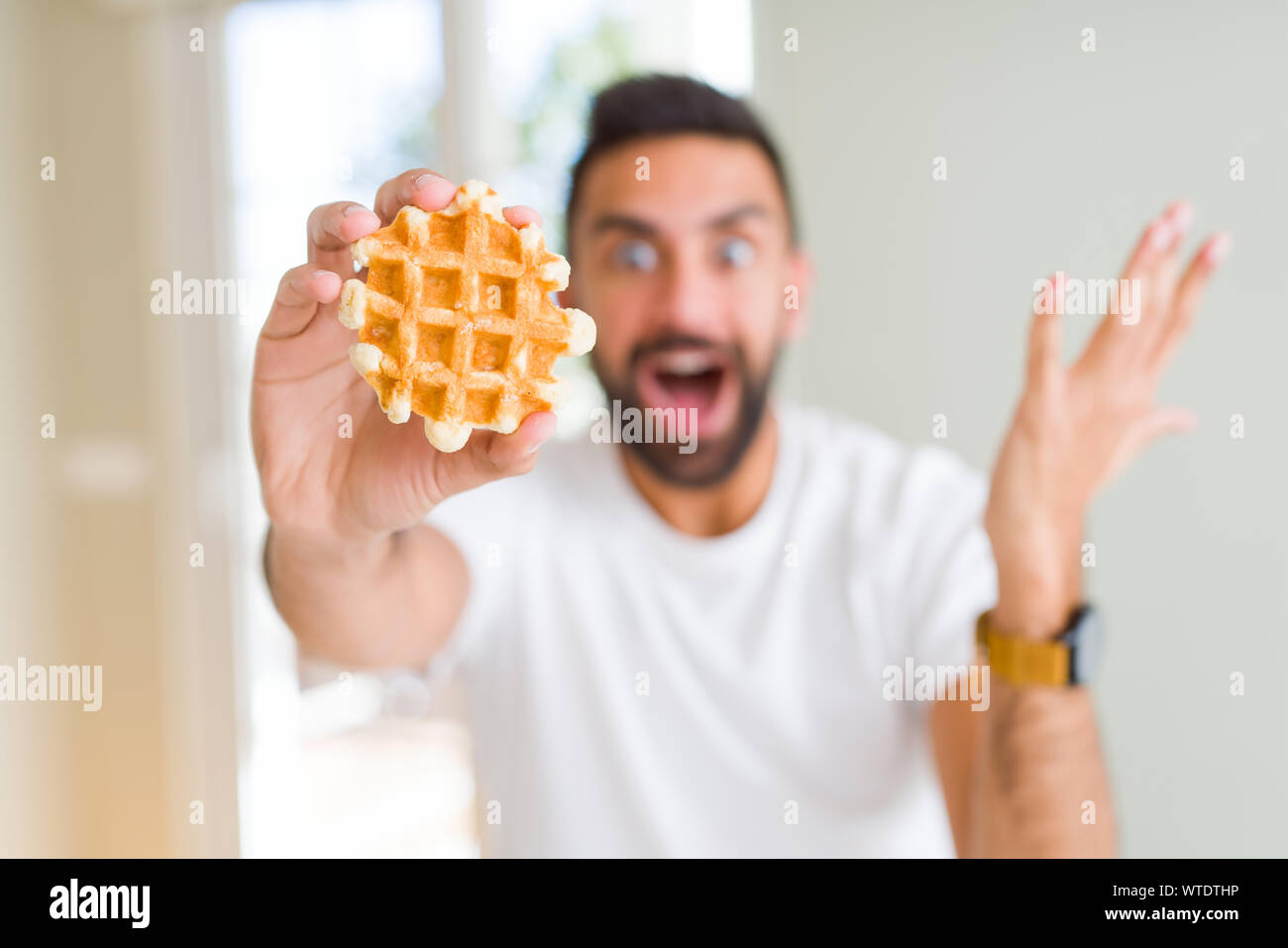 Handsome hispanic man eating sweet belgian waffle pastry very happy and ...