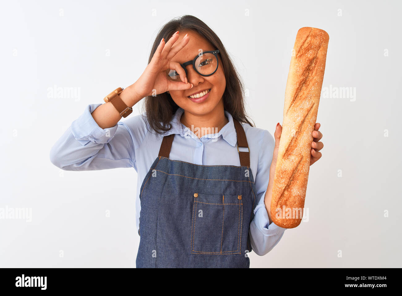 Young chinese baker woman wearing glasses holding bread over isolated ...