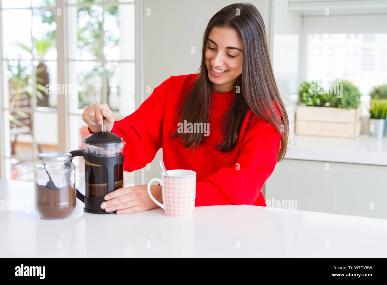 Young beautiful woman making morning coffee smiling, preparing a cup of ...
