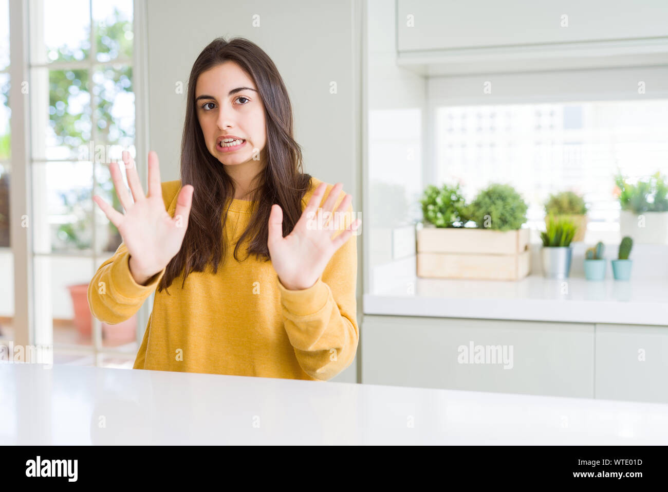 Beautiful young woman wearing yellow sweater afraid and terrified with ...