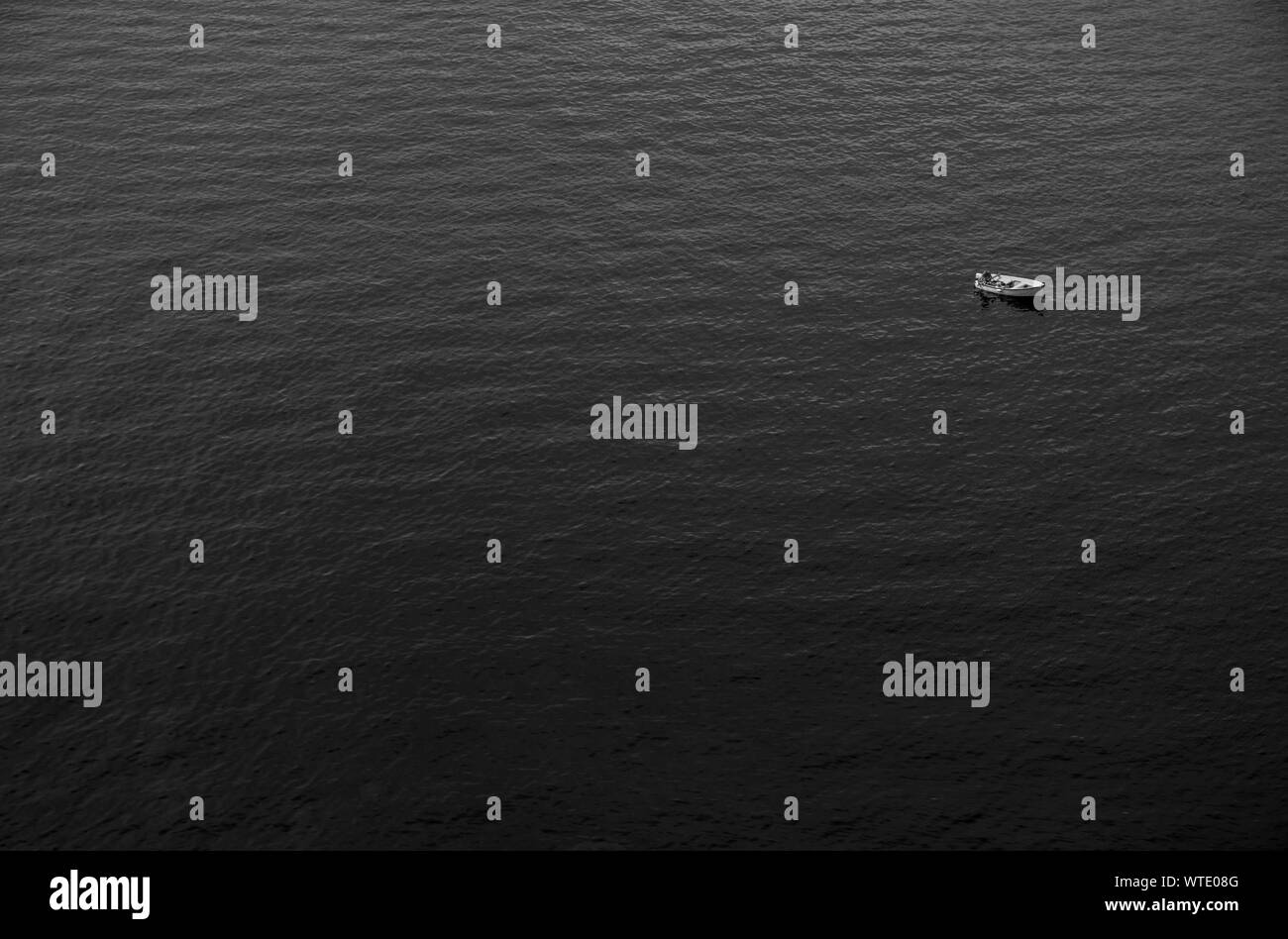 A black and white picture of a small fishing boat alone in the vastness ...