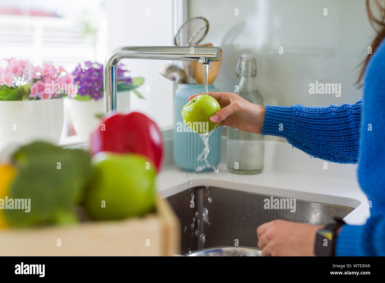 Young woman washing vegetables and fruit using water from sink Stock ...
