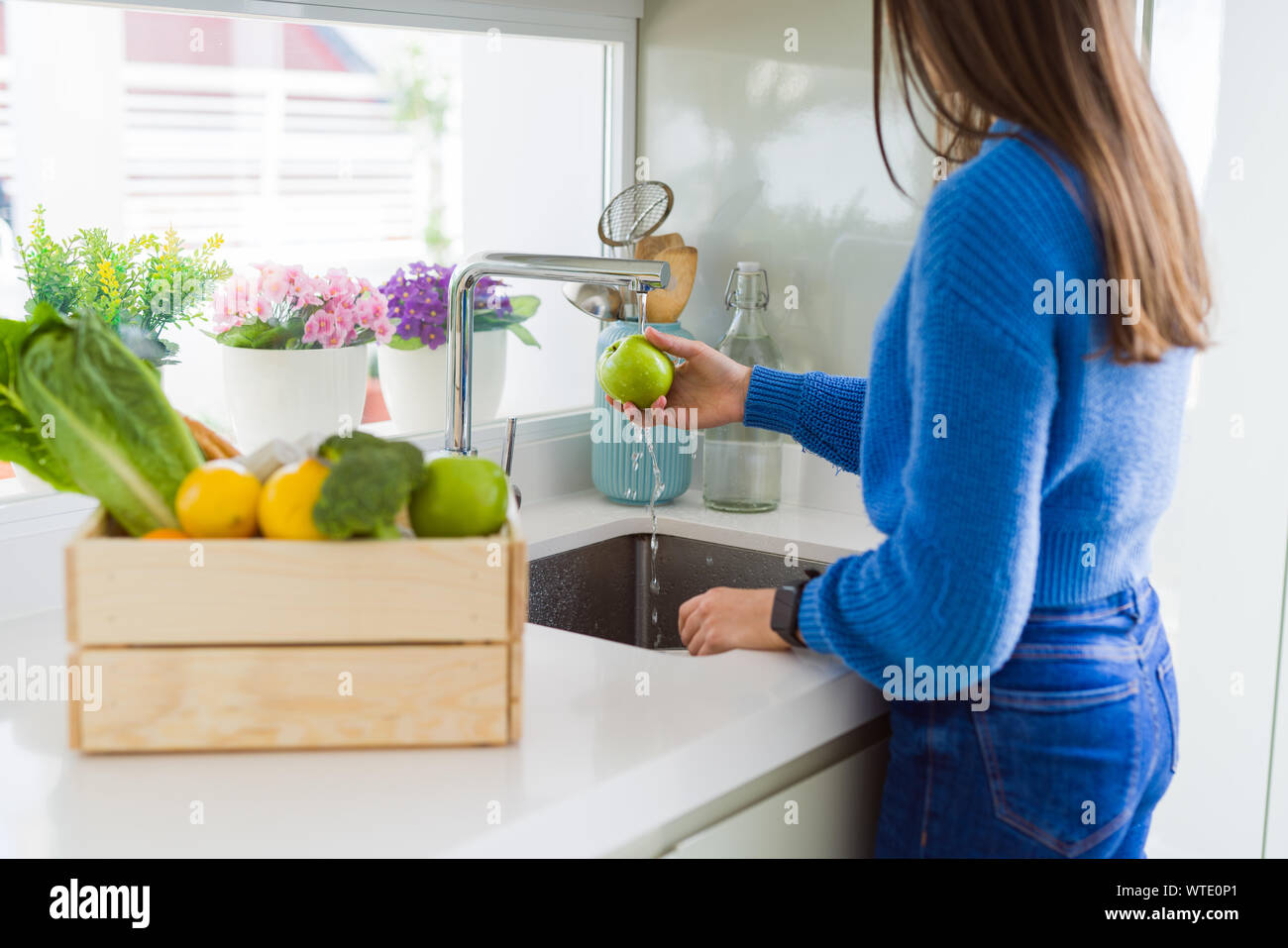 Young woman washing vegetables and fruit using water from sink Stock ...