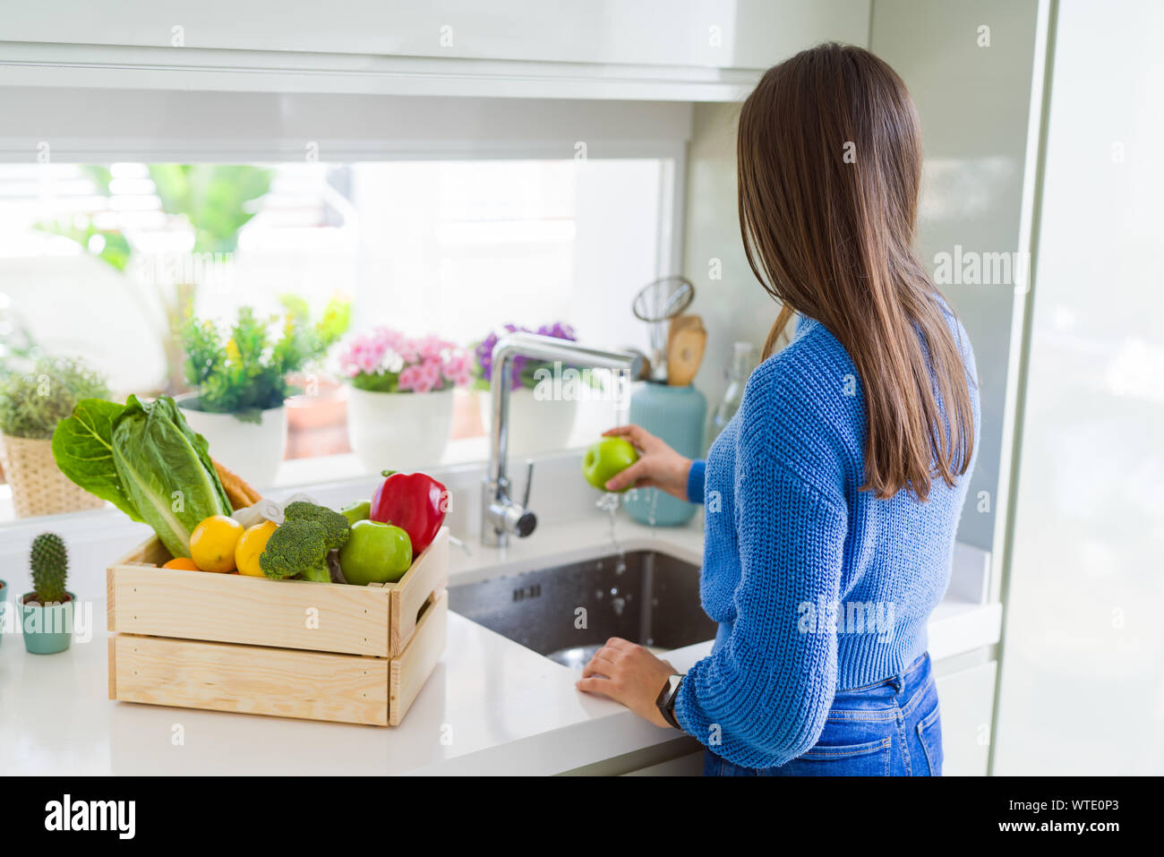 Young woman washing vegetables and fruit using water from sink Stock ...