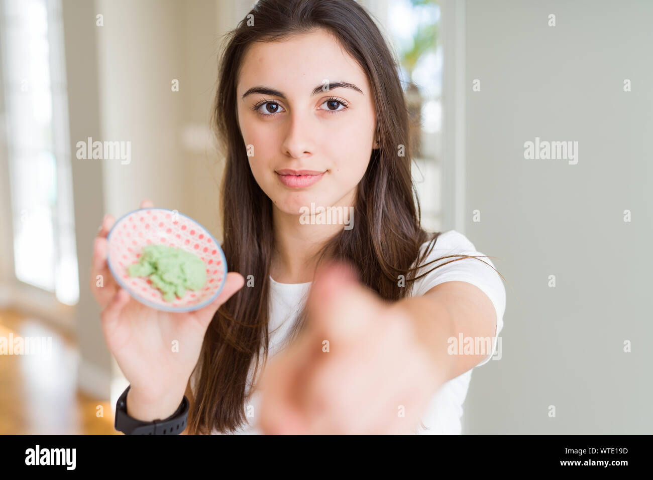 Beautiful young woman holding spicy asian wasabi pointing with finger ...
