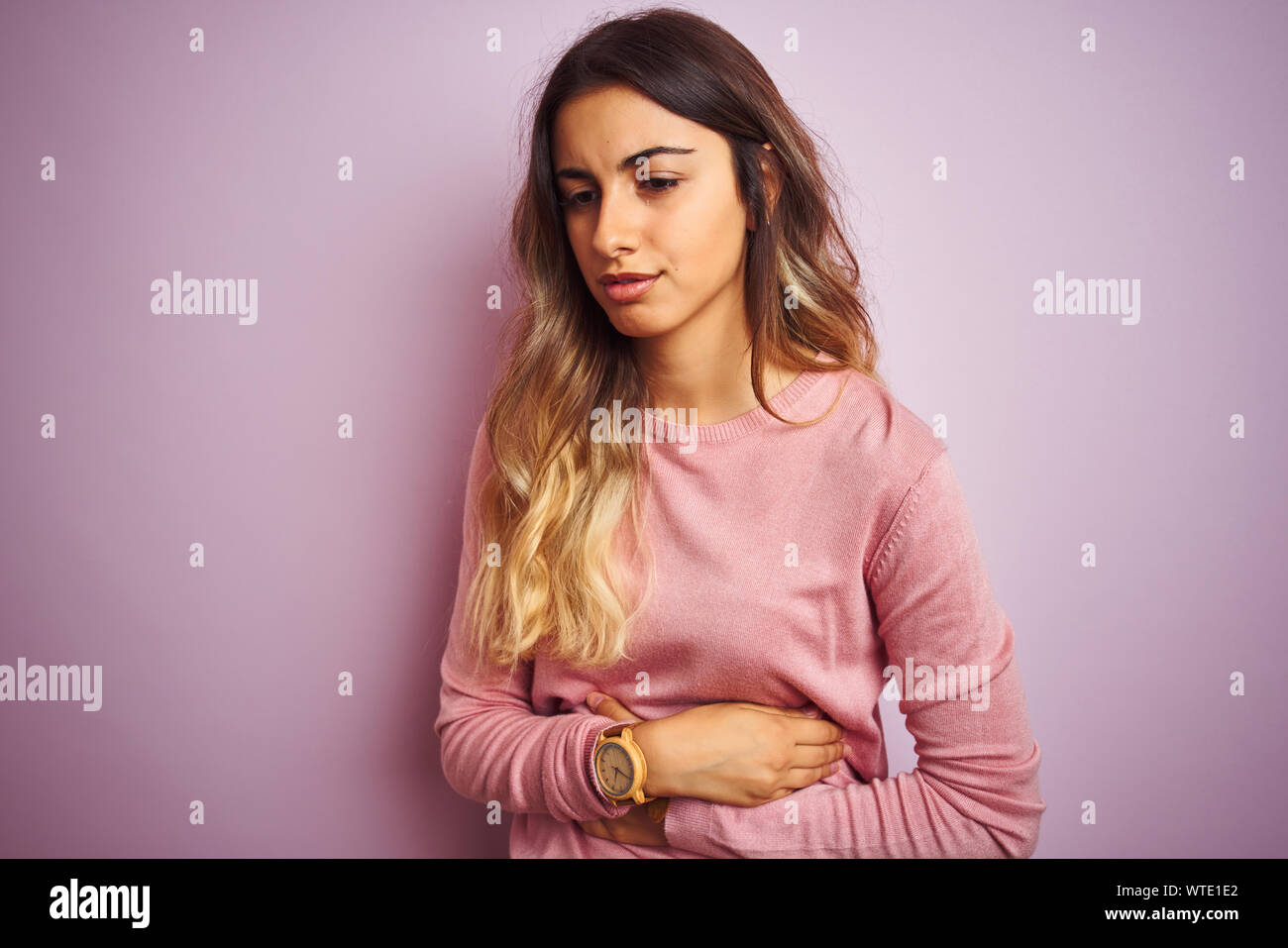 Young beautiful woman wearing a sweater over pink isolated background ...