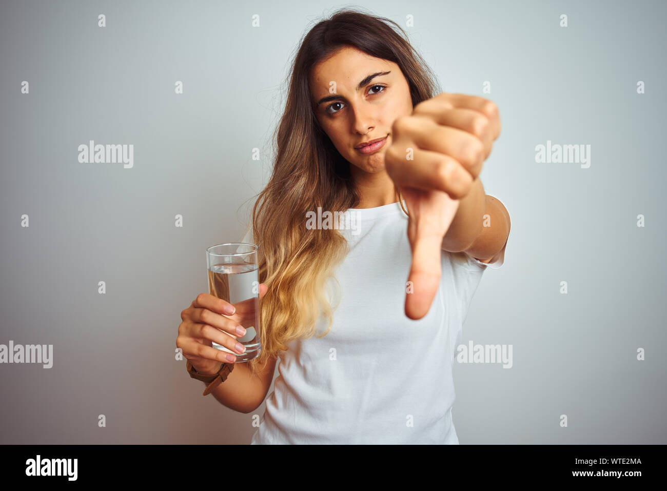 Young beautiful woman drinking a glass of water over white isolated ...