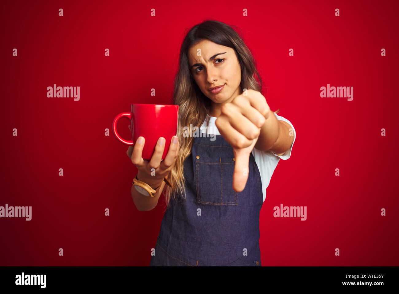 Young beautiful barista woman wearing apron over red isolated ...