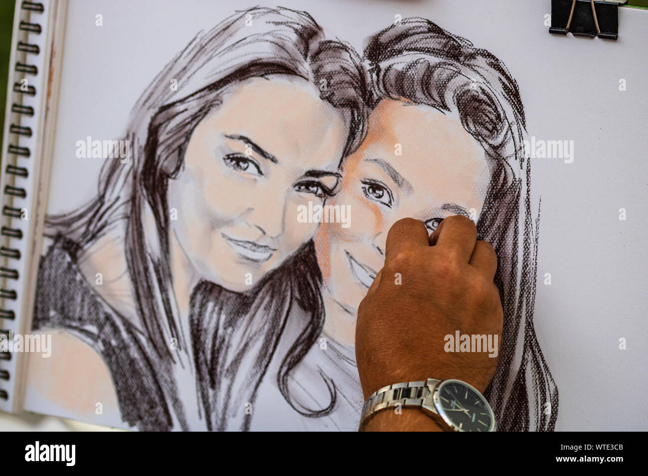 Local artist hand drawing a portrait on the street at a festival in ...
