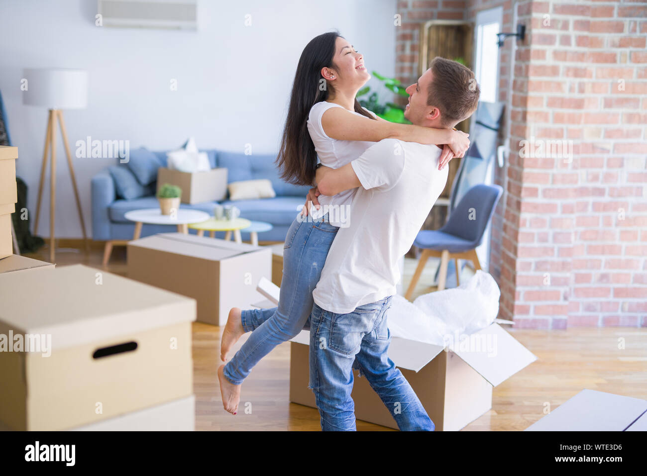 Young beautiful couple hugging at new home around cardboard boxes Stock ...