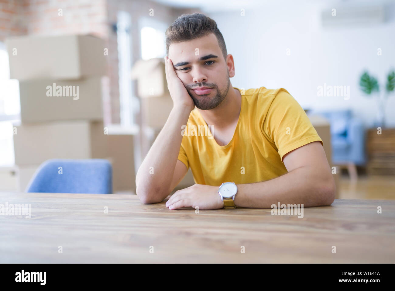 Young man sitting on the table with cardboard boxes behind him moving ...