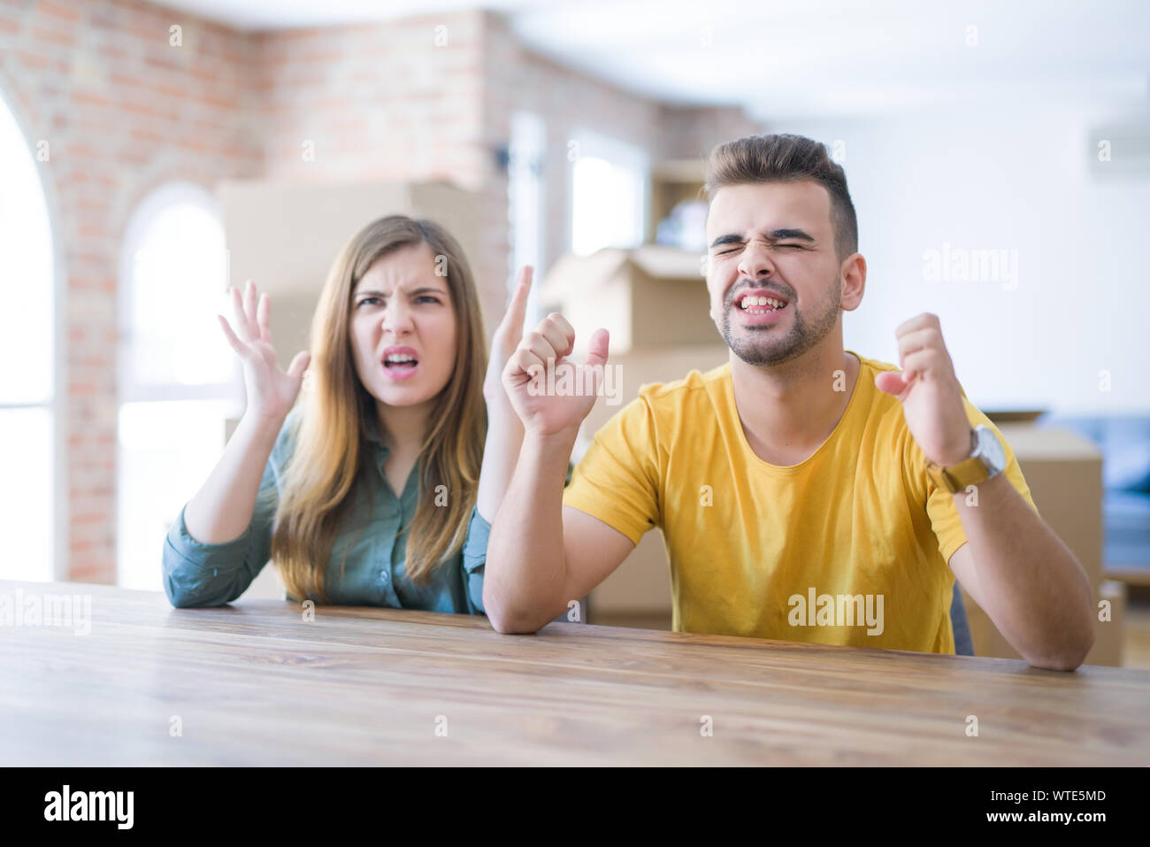 Young couple sitting on the table movinto to new home with carboard ...