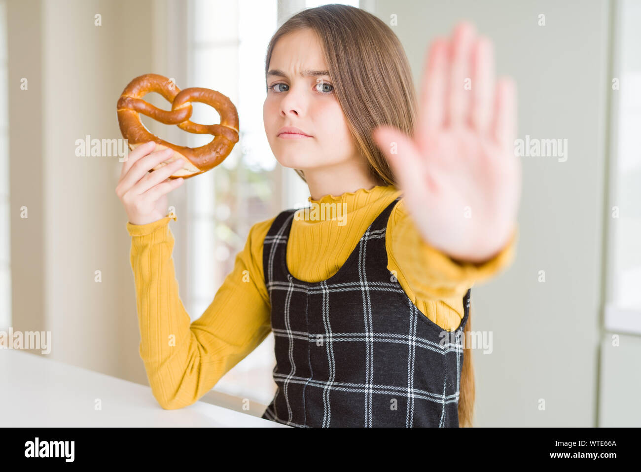 Beautiful young girl kid eating german snack salty pretzel with open ...