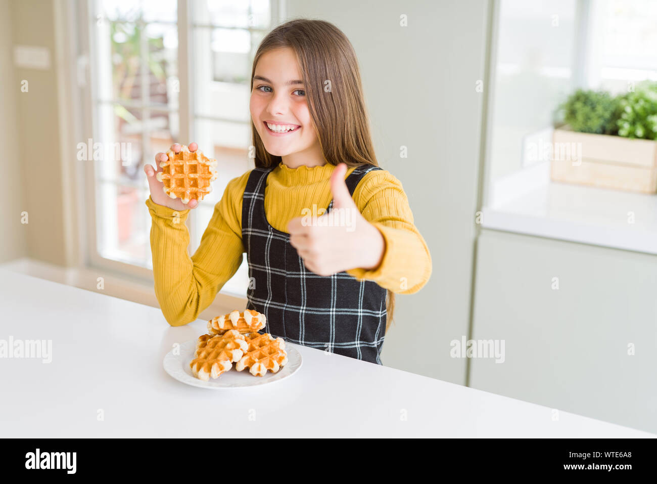 Beautiful young girl kid eating Belgian waffle pastry happy with big ...