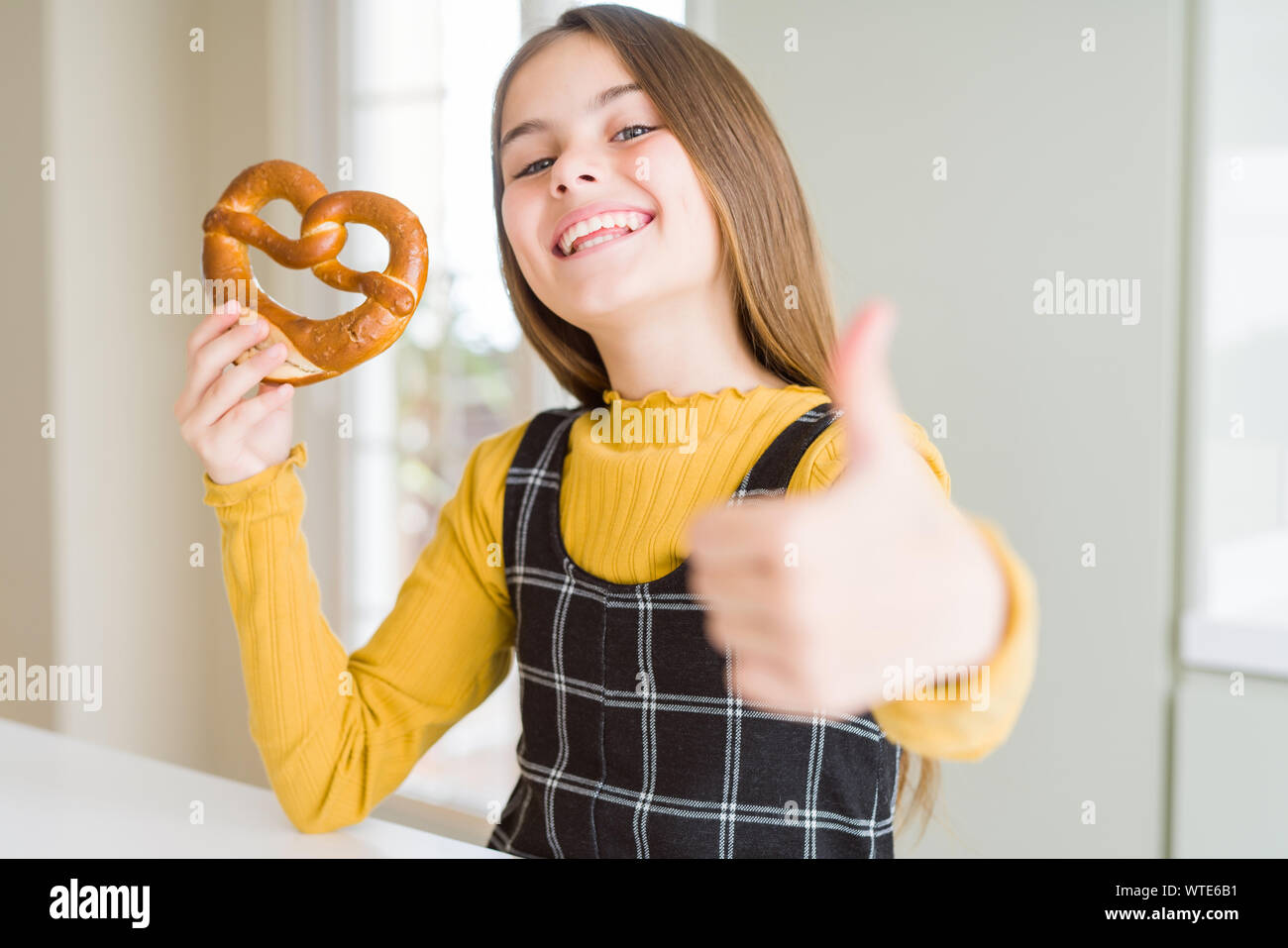 Beautiful young girl kid eating german snack salty pretzel happy with ...