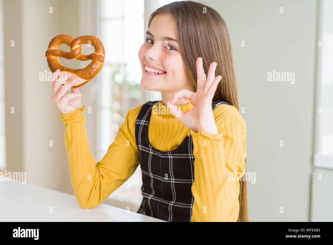 Beautiful young girl kid eating german snack salty pretzel doing ok ...