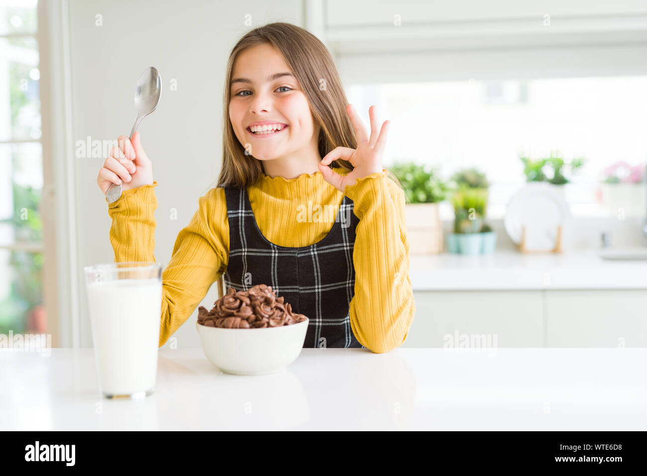 Beautiful young girl kid eating chocolate cereals and glass of milk for ...