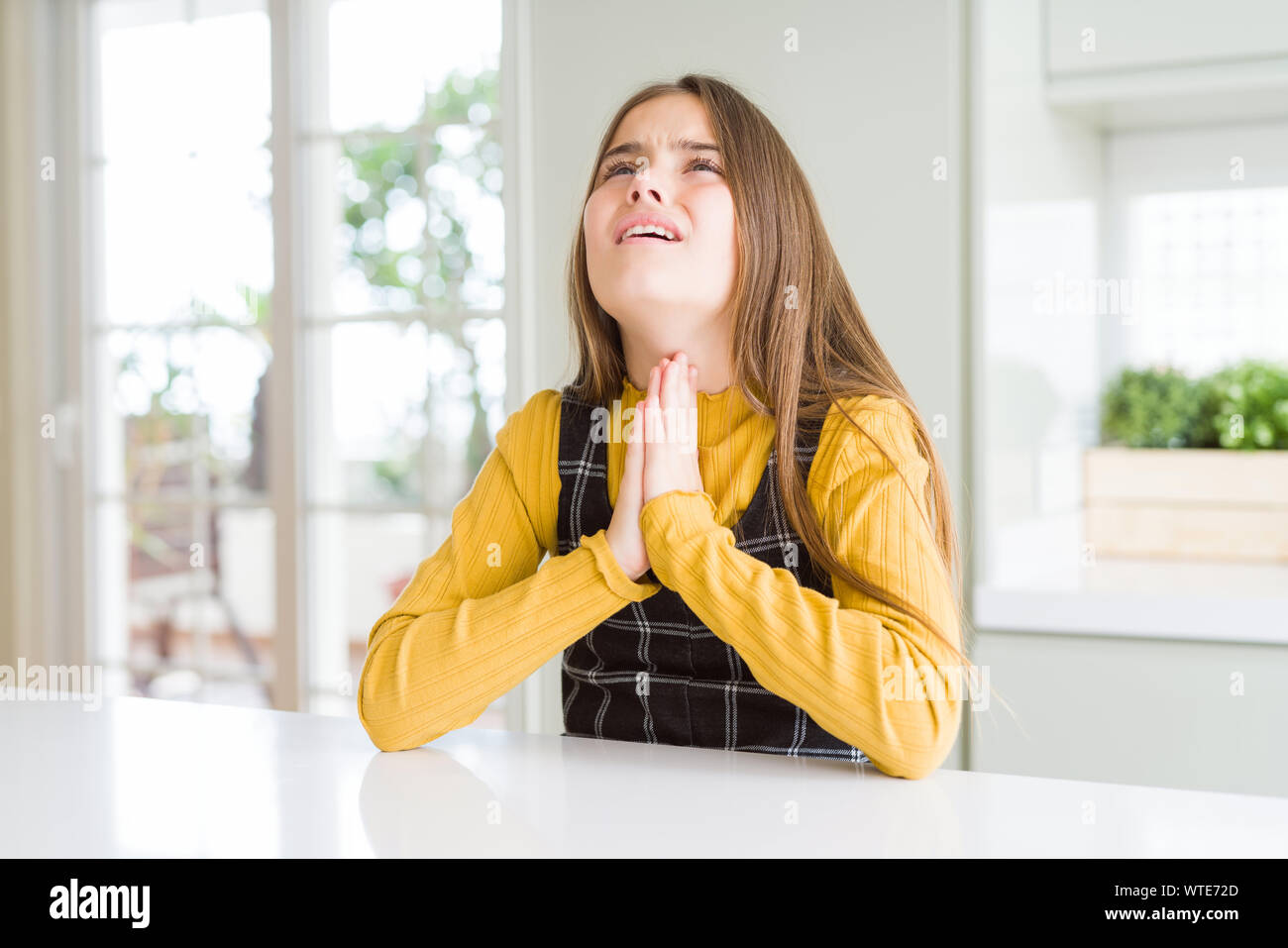 Young beautiful blonde kid girl wearing casual yellow sweater at home ...