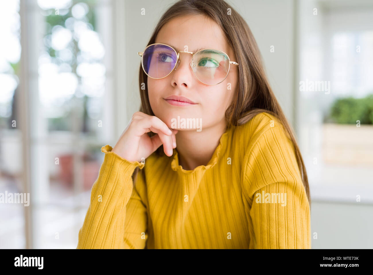 Beautiful young girl kid wearing glasses with hand on chin thinking ...