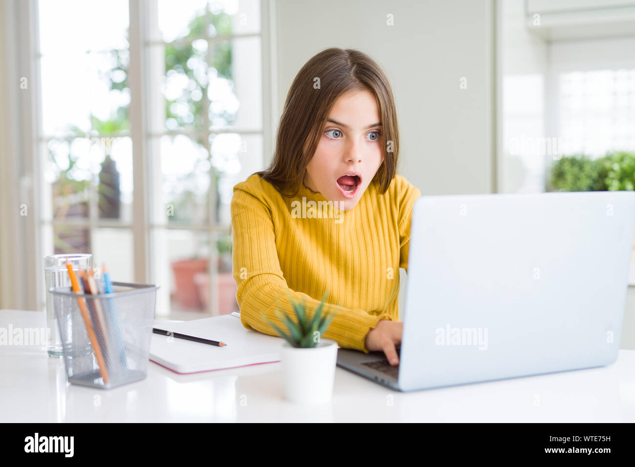 Beautiful young girl studying for school using computer laptop scared ...