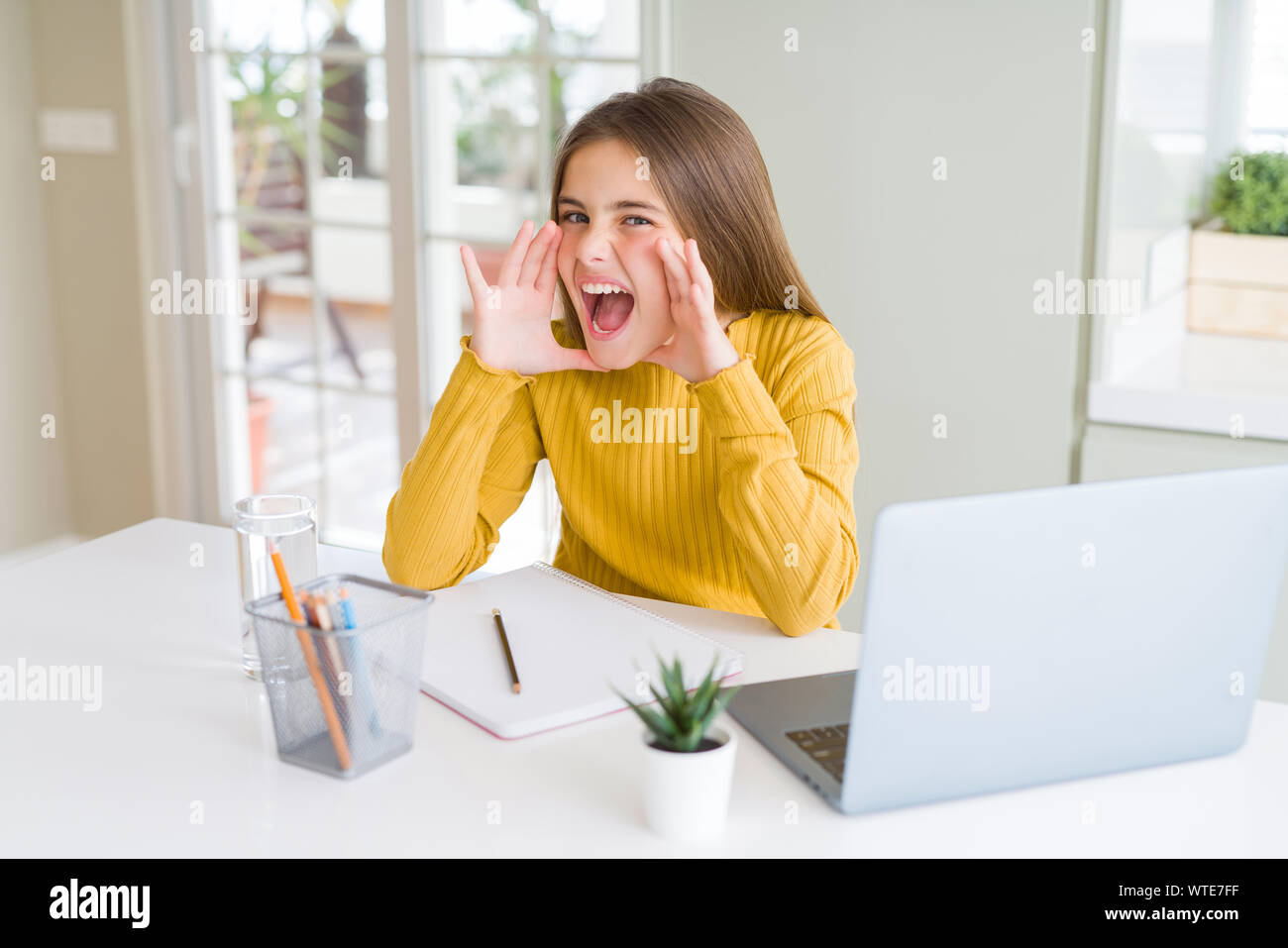 Beautiful young girl studying for school using computer laptop shouting ...