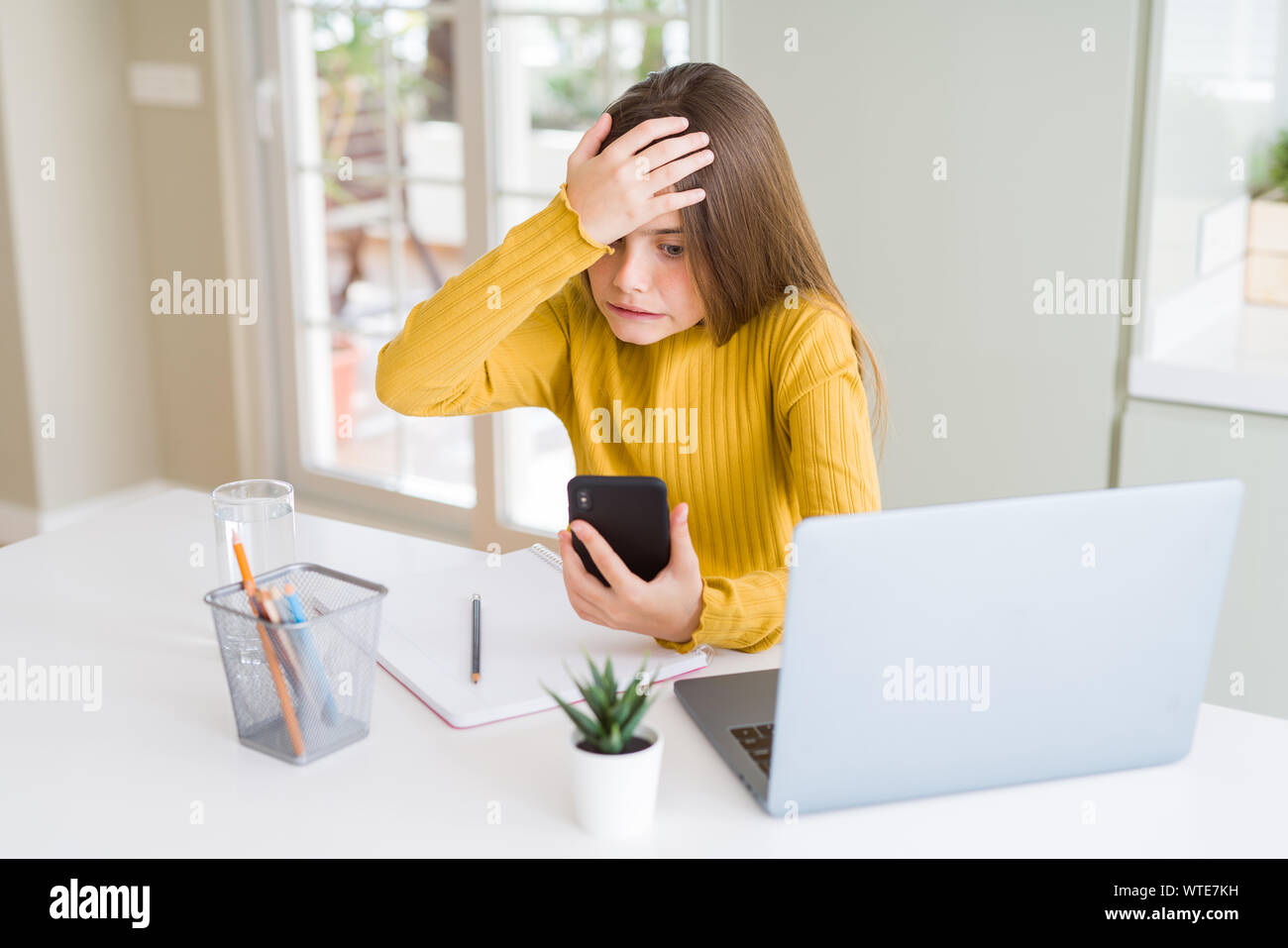 Beautiful young girl kid using smartphone and computer laptop stressed ...