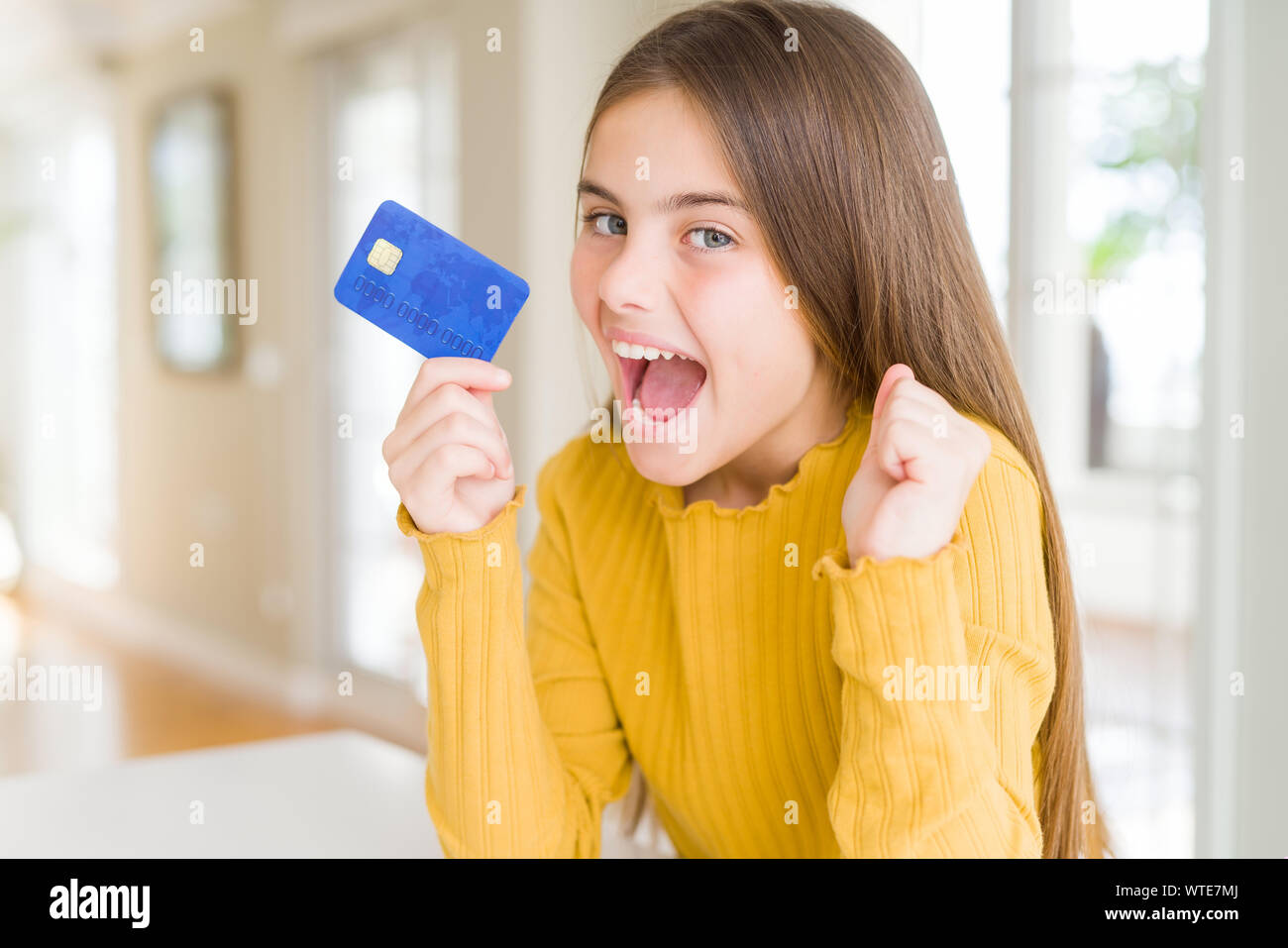 Beautiful young girl kid holding credit card screaming proud and ...