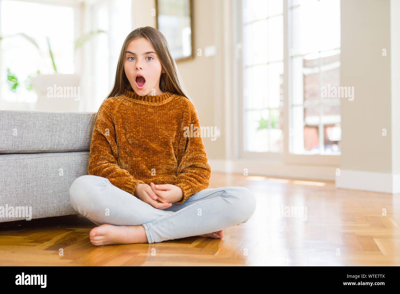 Beautiful young girl kid sitting on the floor at home afraid and ...