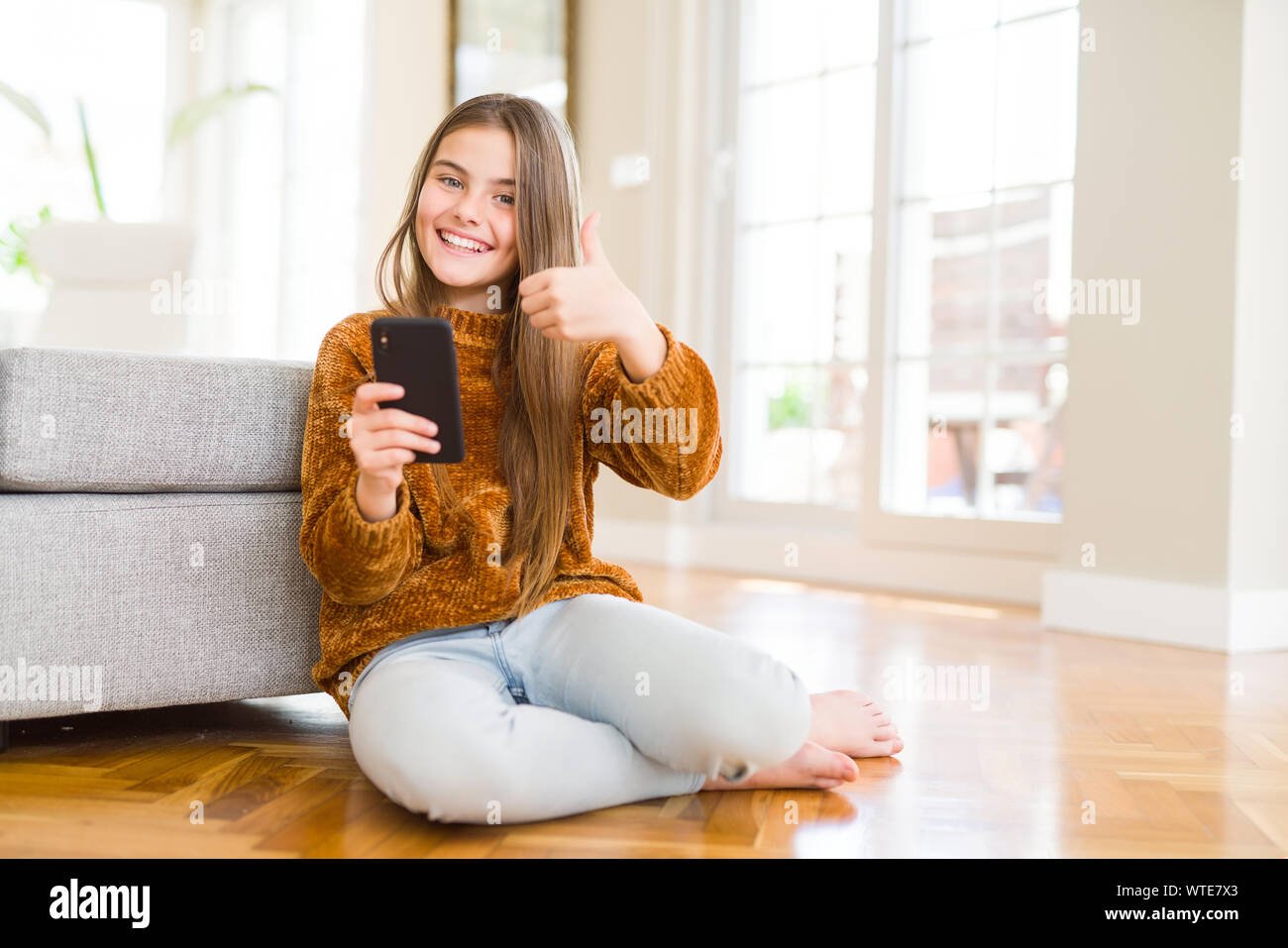Beautiful young girl kid sending a message using smartphone happy with ...