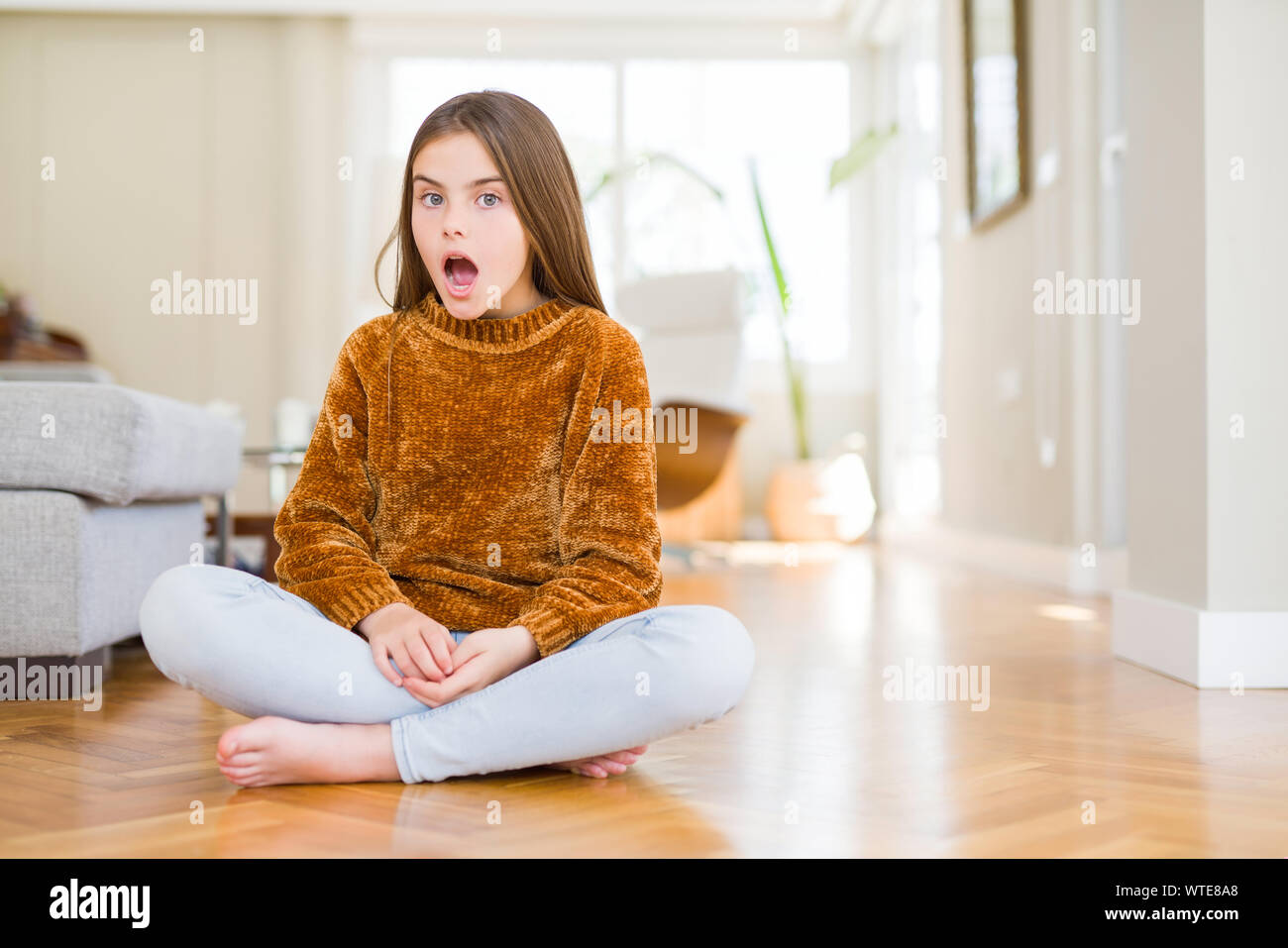 Beautiful young girl kid sitting on the floor at home afraid and ...