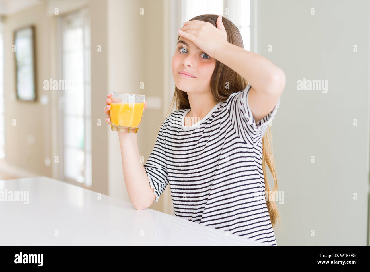 Beautiful young girl kid drinking a glass of fresh orange juice ...