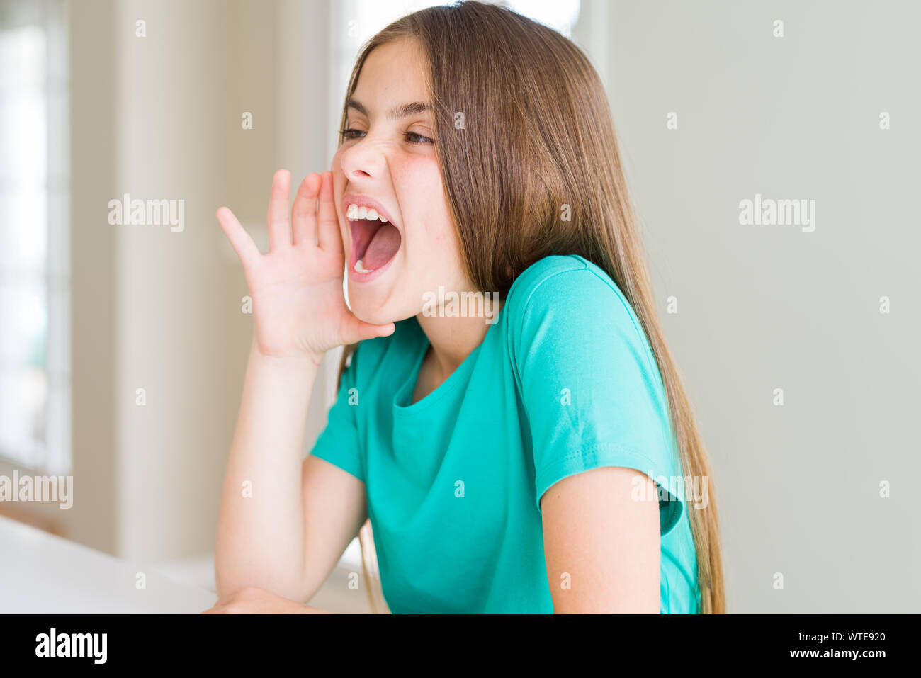 Beautiful young girl kid wearing green t-shirt shouting and screaming ...