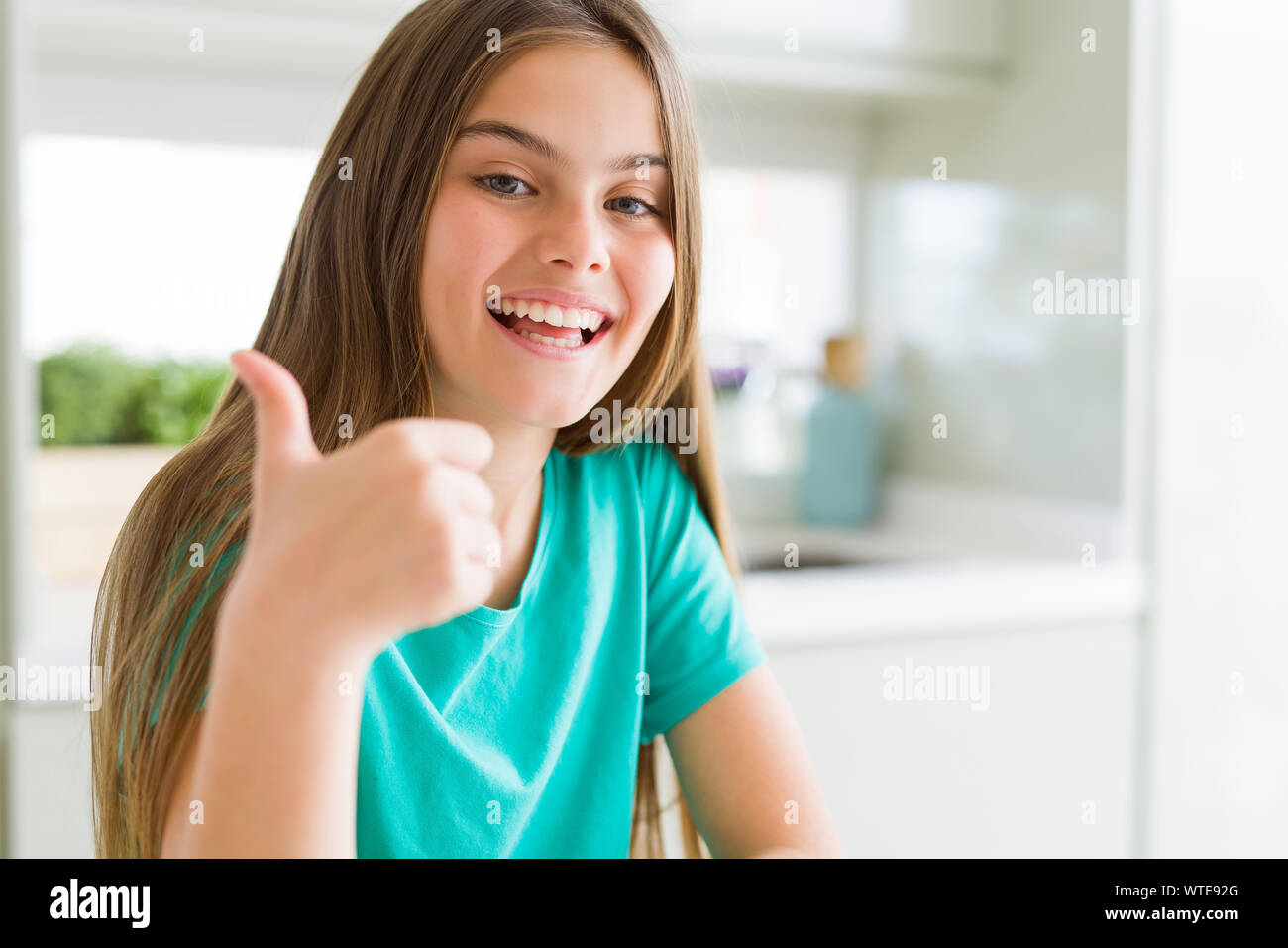 Beautiful young girl kid wearing green t-shirt doing happy thumbs up ...