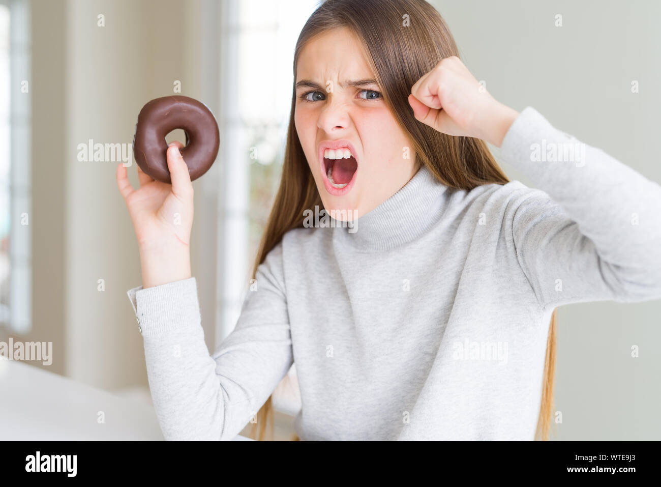 Beautiful young girl wearing eating a chocolate donut annoyed and ...