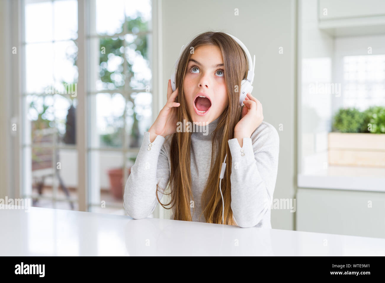 Beautiful young girl wearing headphones listening to music and dancing ...