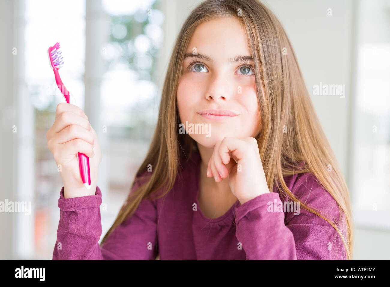Beautiful young girl kid holding pink dental toothbrush serious face ...