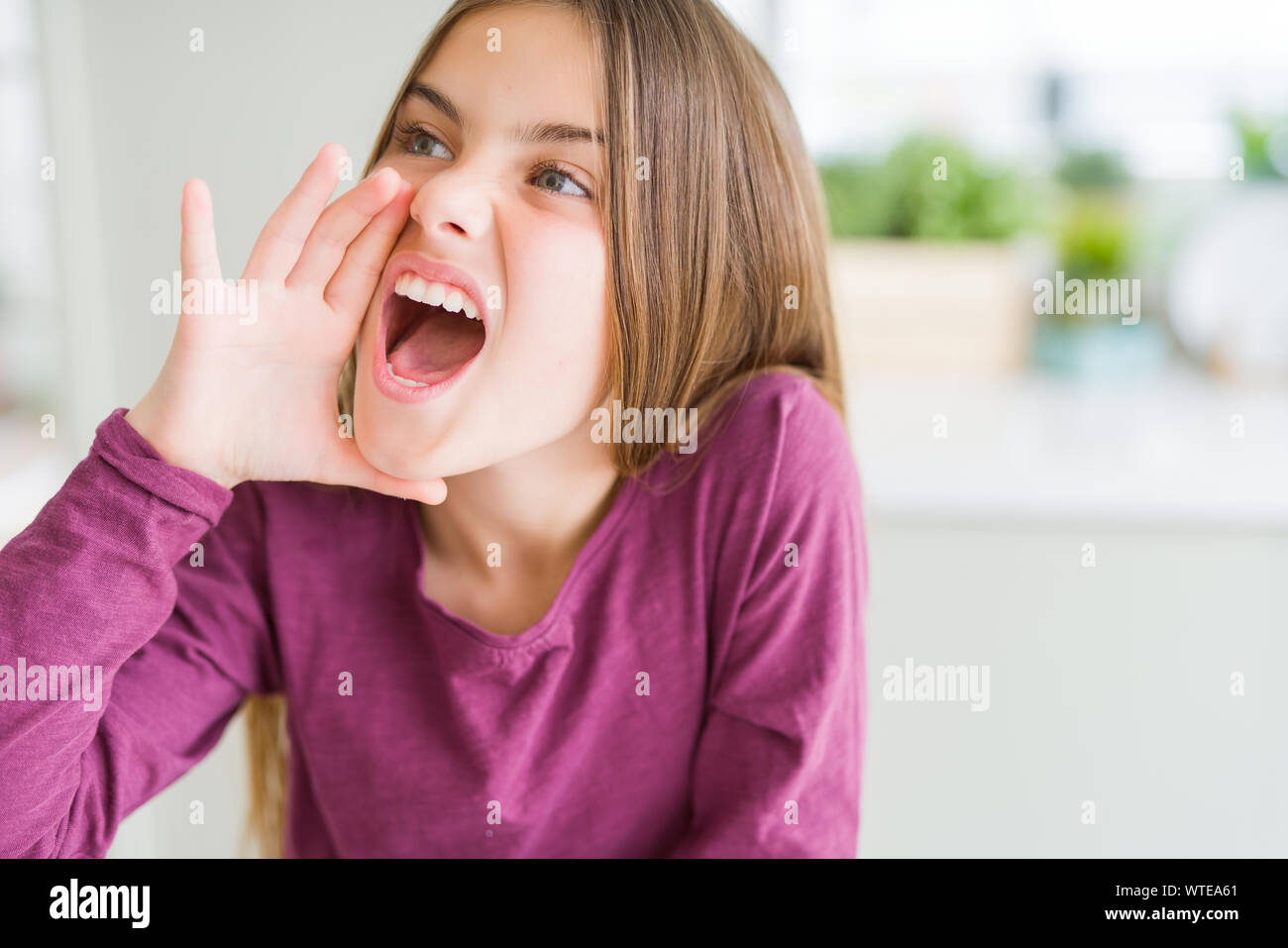Beautiful young girl kid shouting and screaming loud to side with hand ...