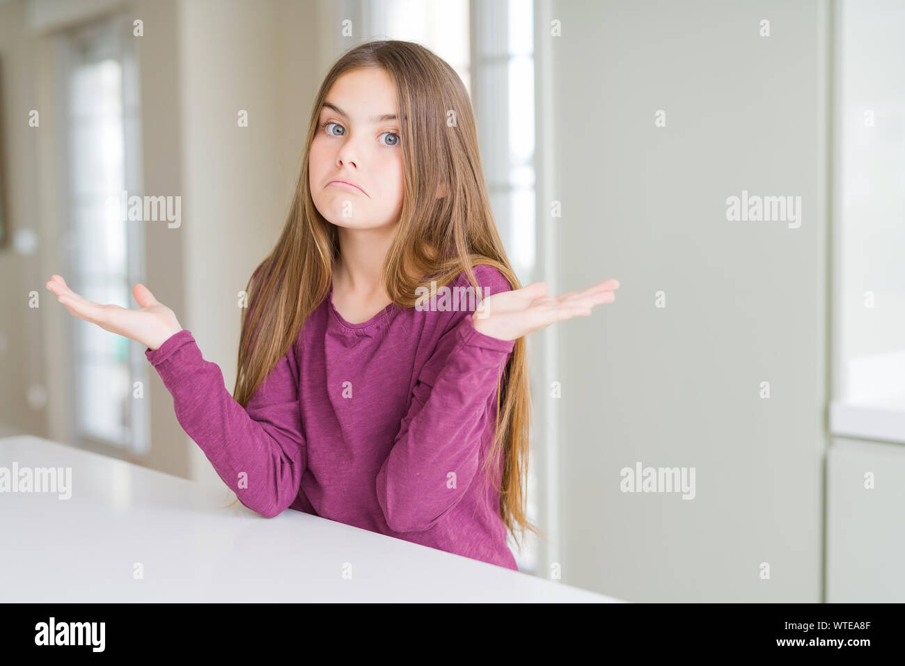 Beautiful young girl kid on white table clueless and confused ...