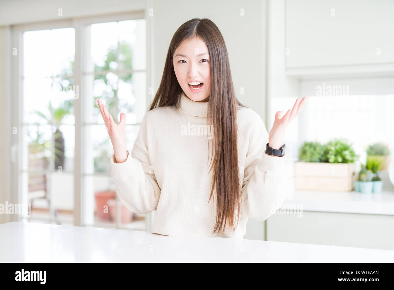 Beautiful Asian woman wearing casual sweater crazy and mad shouting and ...