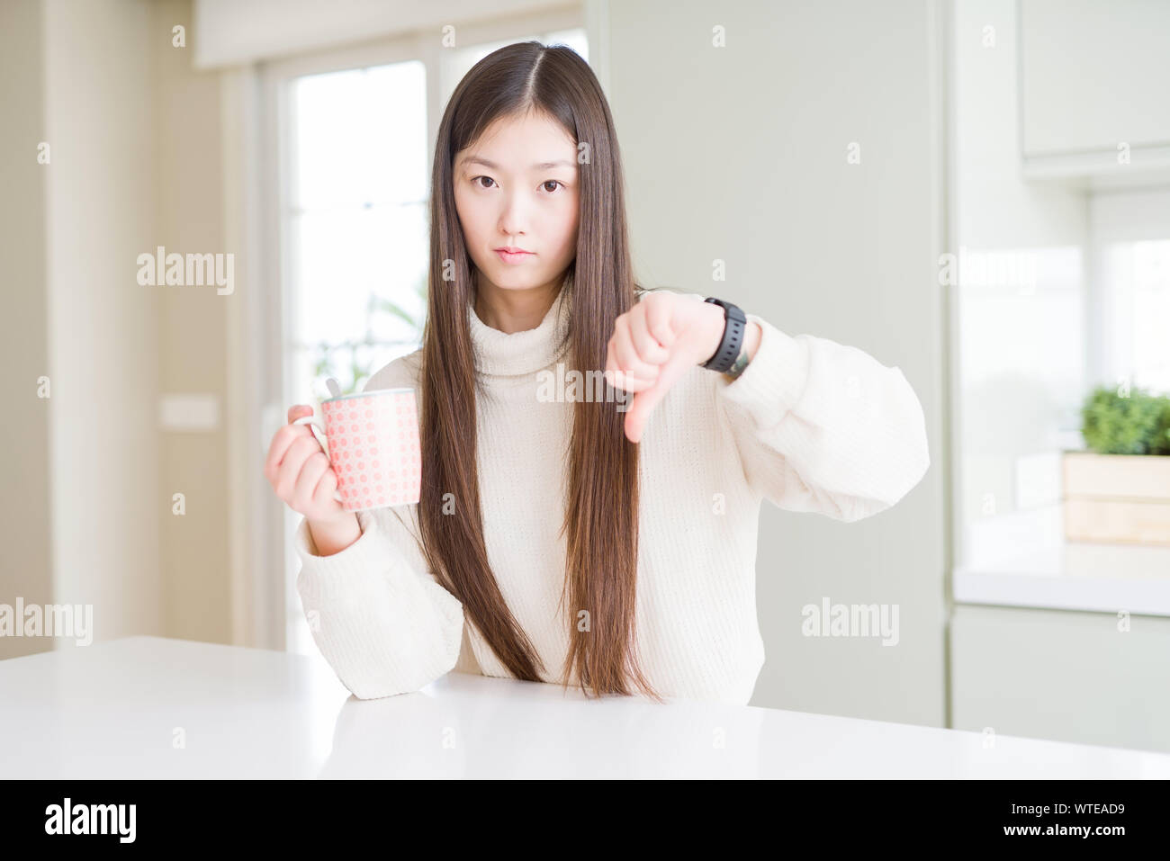 Beautiful Asian woman drinking a cup of coffee with angry face ...