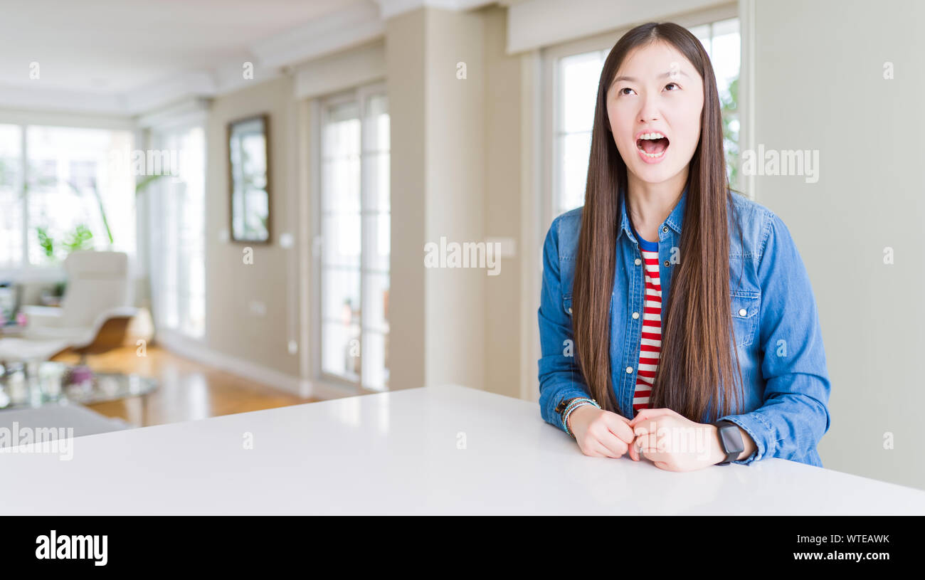 Young beautiful asian woman with long hair wearing denim jacket angry ...