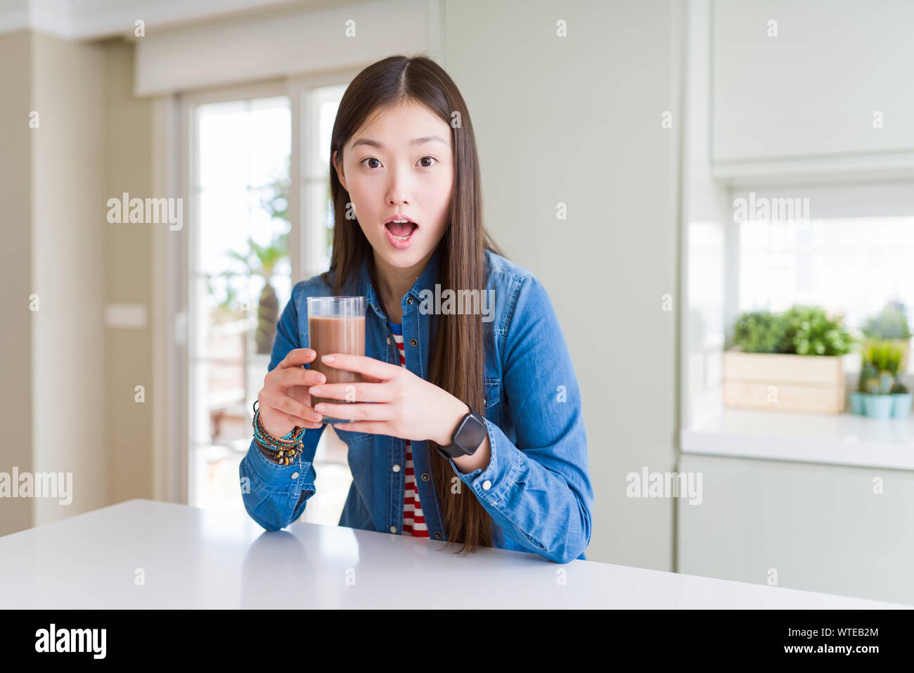Beautiful Asian woman drinking a fresh glass of chocolate milkshake ...