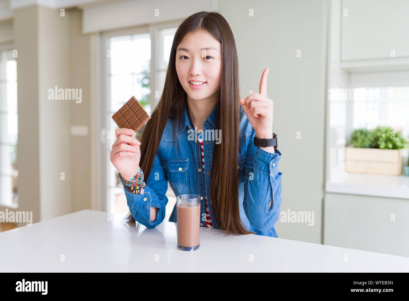 Beautiful Asian woman drinking chocolate milkshake and holding ...