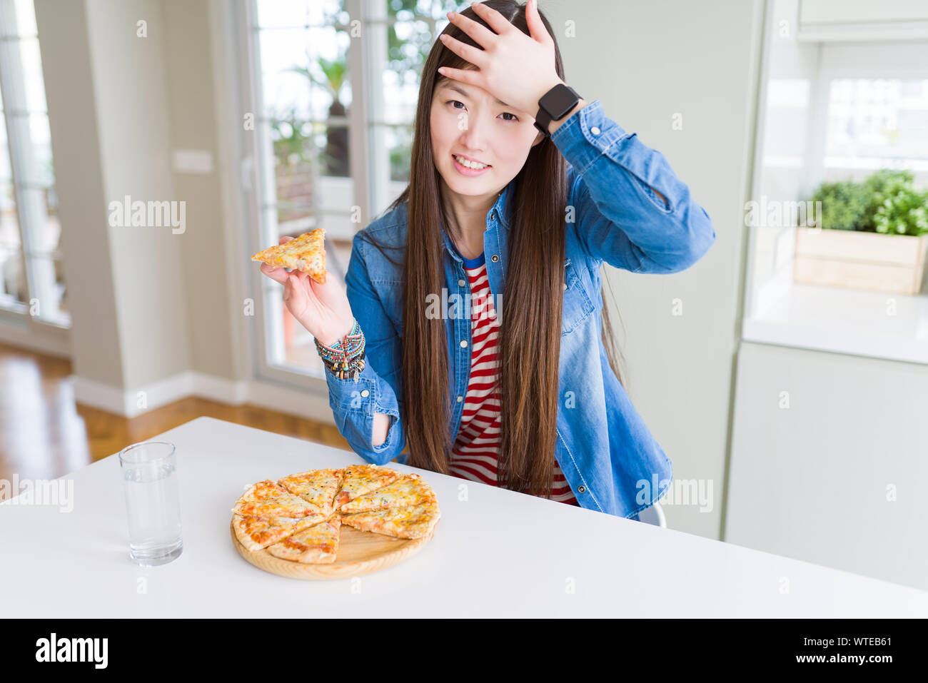 Beautiful Asian woman eating a slice of cheese pizza stressed with hand ...