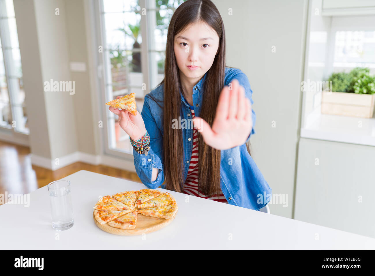 Beautiful Asian woman eating a slice of cheese pizza with open hand ...